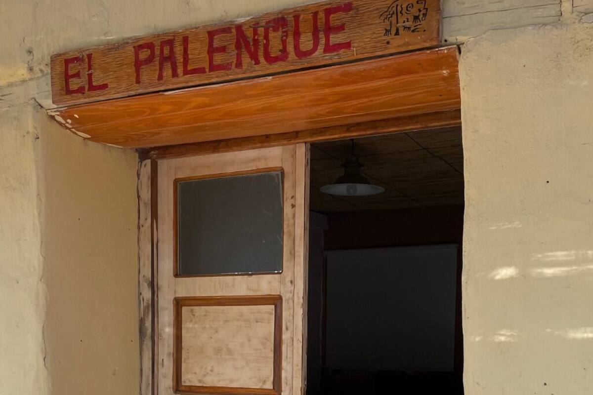 Uma porta de madeira com uma placa acima que diz 'EL PALENQUE'.