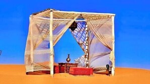 Tenda no deserto com uma mesa e uma cadeira dentro.