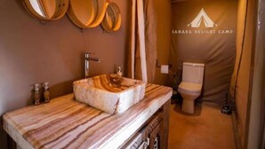 Casa de banho com lavatório de mármore, sanita e cortina de chuveiro.