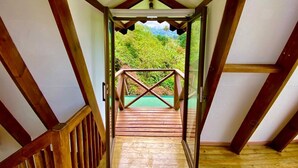 Uma escadaria de madeira leva a uma varanda com vista para o verde.