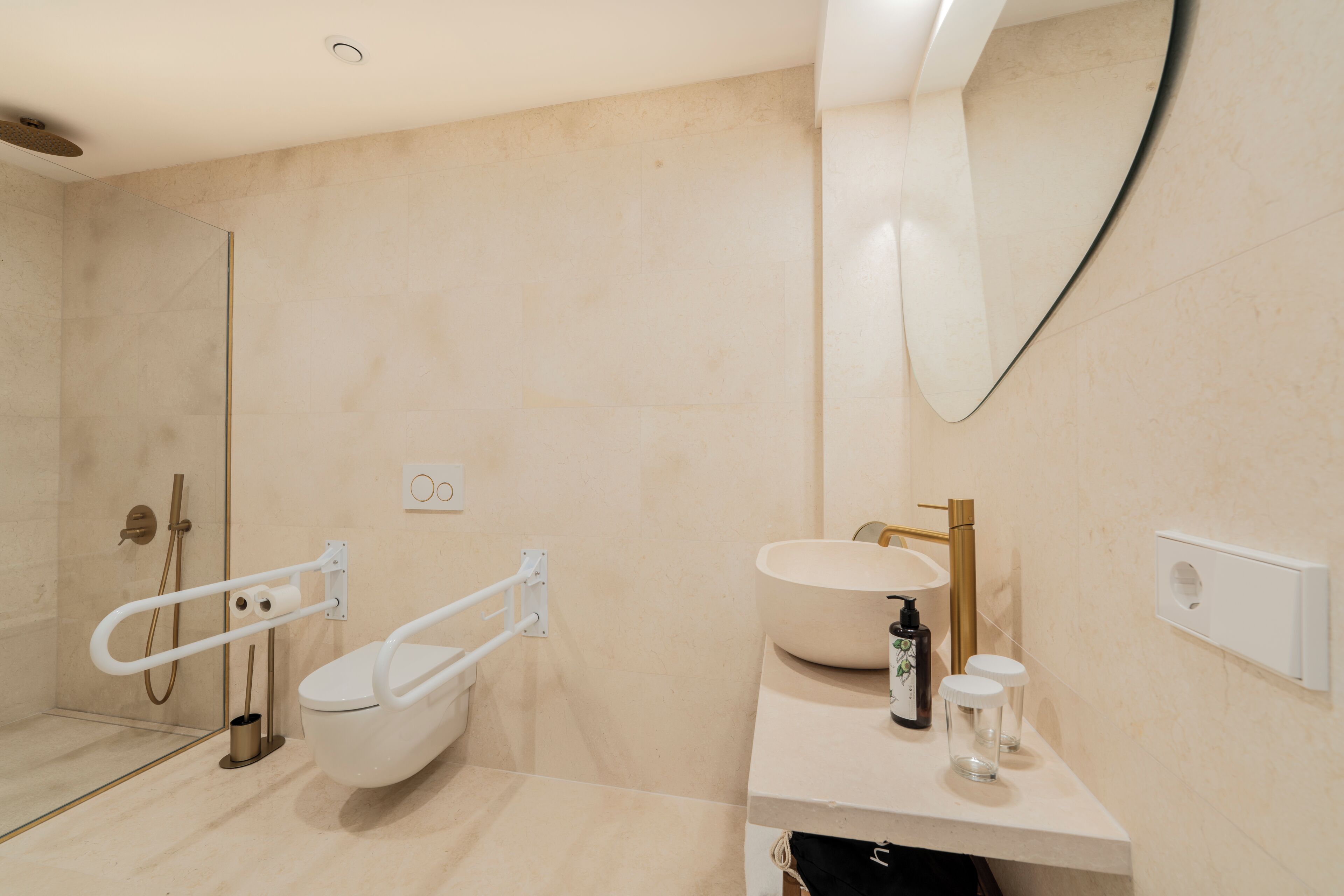 Casa de banho moderna com sanita, bidé e lavatório, equipada com barra de apoio para acessibilidade.