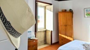 Quarto com uma cama, guarda-roupa de madeira e uma janela.