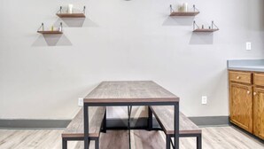 Um quarto com uma mesa de madeira, três prateleiras fixadas na parede e um relógio.