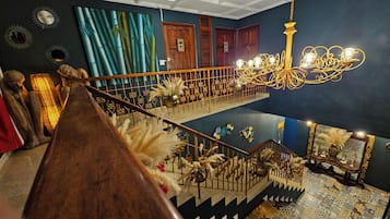 Uma escadaria imponente com grades elaboradas e um candelabro, levando a uma varanda com vista.
