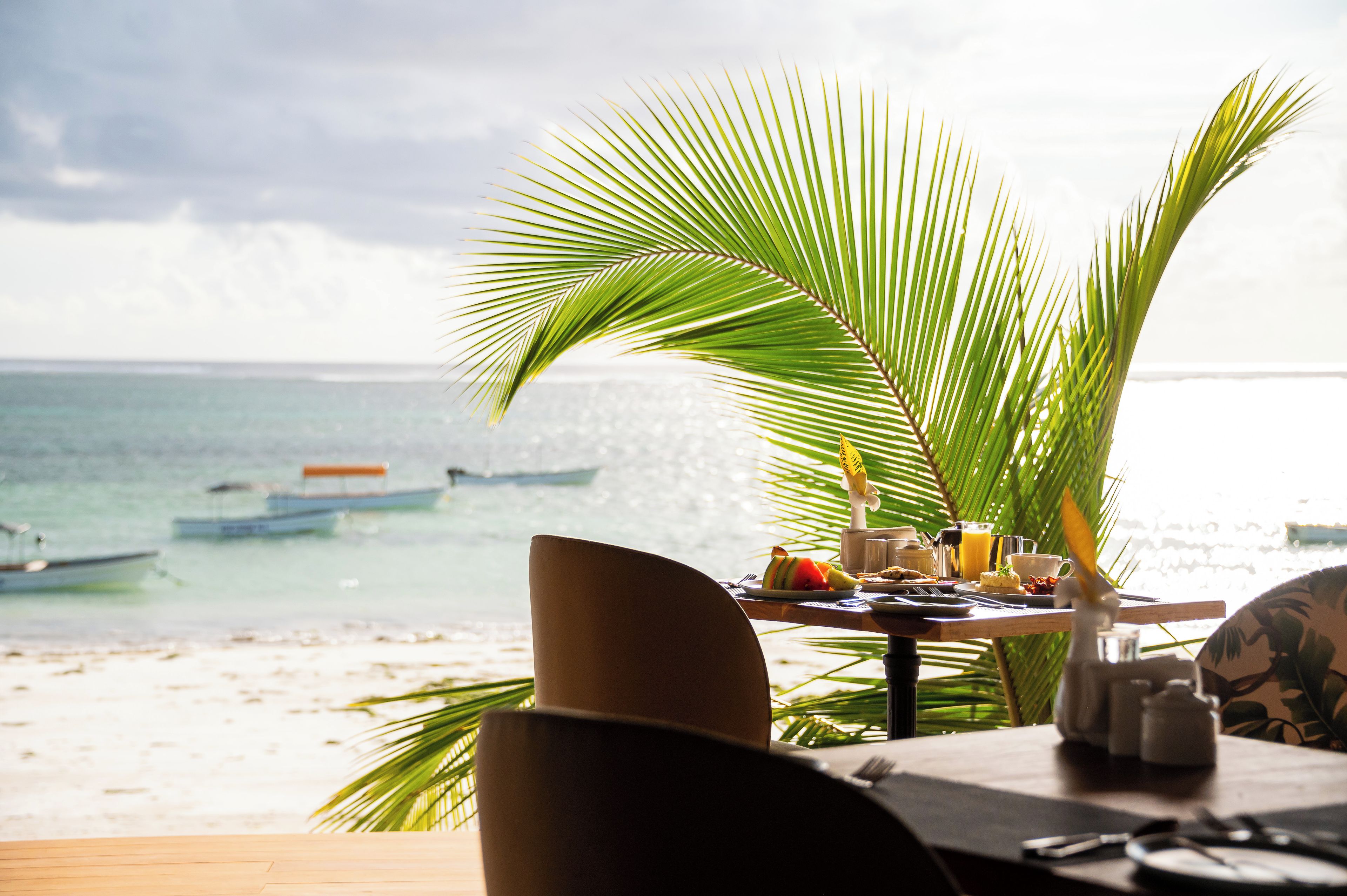 Mesa posta para o café da manhã, com vista para o mar e barcos.