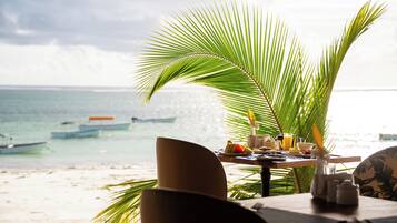 Mesa posta para o café da manhã, com vista para o mar e barcos.