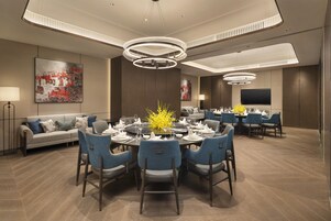 Uma área de jantar moderna com uma mesa redonda, cadeiras azuis e um centro de mesa amarelo.