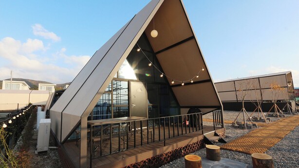 Um edifício moderno em formato triangular, com varanda e luzes de fada.