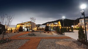 Um edifício moderno com grandes janelas e áreas de estar ao ar livre, cercado por cascalho e árvores pequenas.