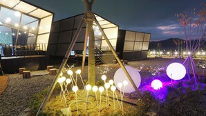 Um edifício moderno com grandes janelas de vidro e uma estrutura geométrica singular na frente.