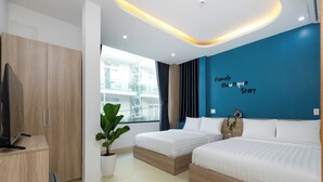 Quarto de hotel com duas camas, televisão, planta em vaso e vista para o edifício.