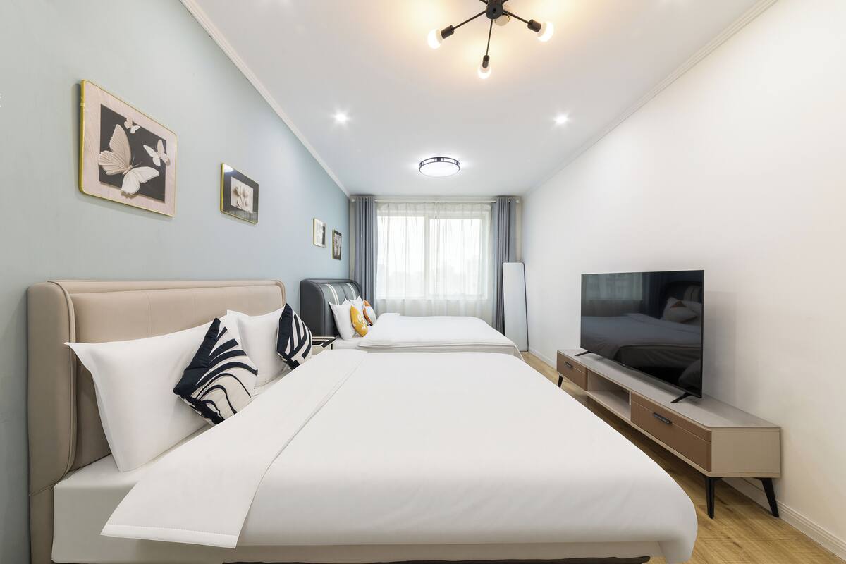 Quarto de hotel moderno com uma cama grande, televisão e obras de arte nas paredes.