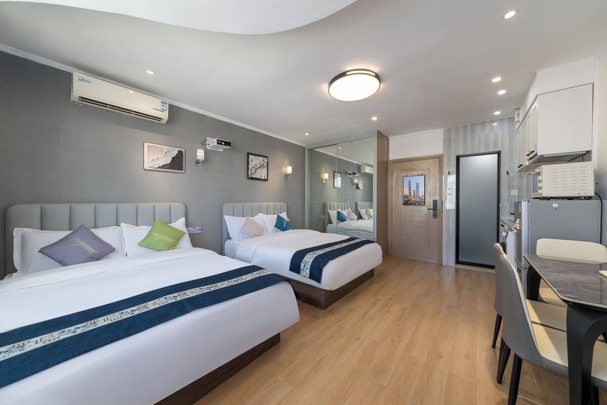 Quarto de hotel com duas camas, área de refeições e cozinha.