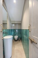 Um banheiro moderno com uma pia grande e branca, vaso sanitário e espelho.