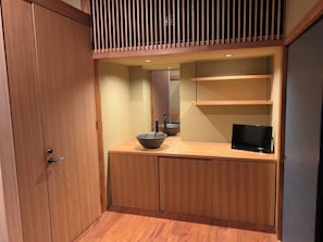 Uma casa de banho moderna com toucador de madeira, lavatório e espelho.