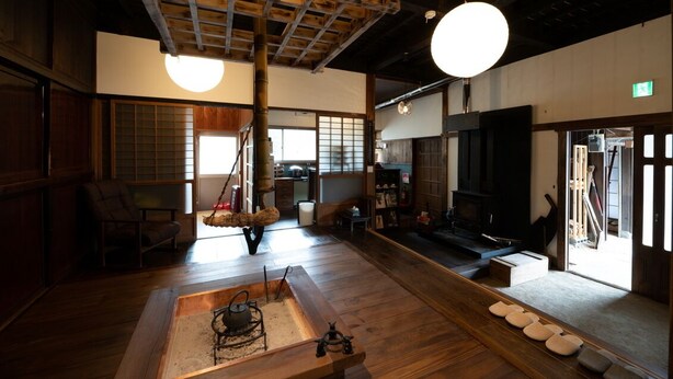 Um interior japonês tradicional com tatames, uma mesa de madeira baixa, lareira e portas deslizantes.