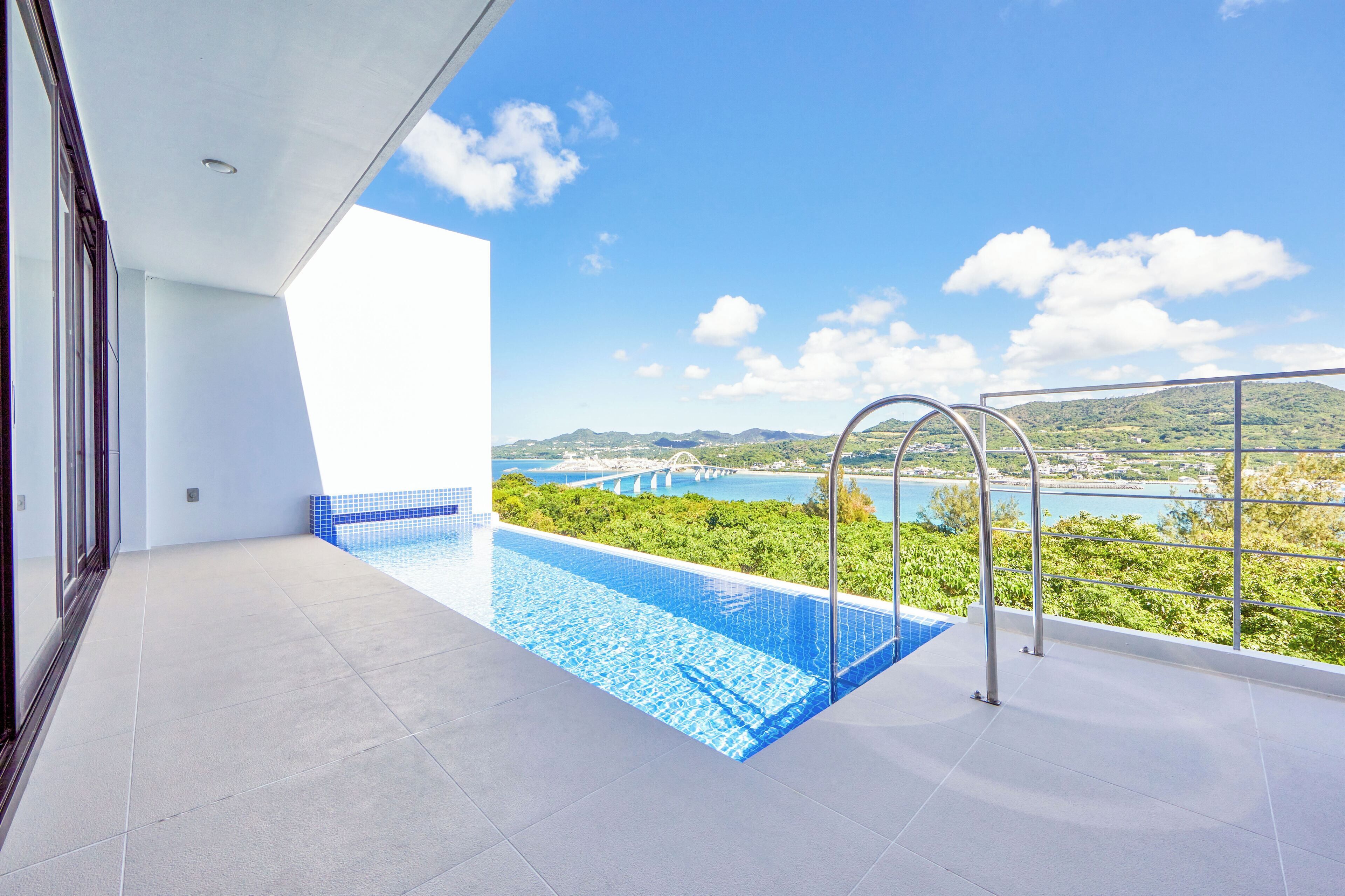 Uma piscina ao ar livre moderna com vista desobstruída para uma ponte e colinas ao fundo.