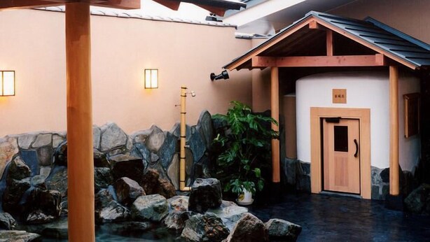 Um edifício tradicional em estilo japonês, com um pátio de pedra, estrutura de madeira e porta de madeira.