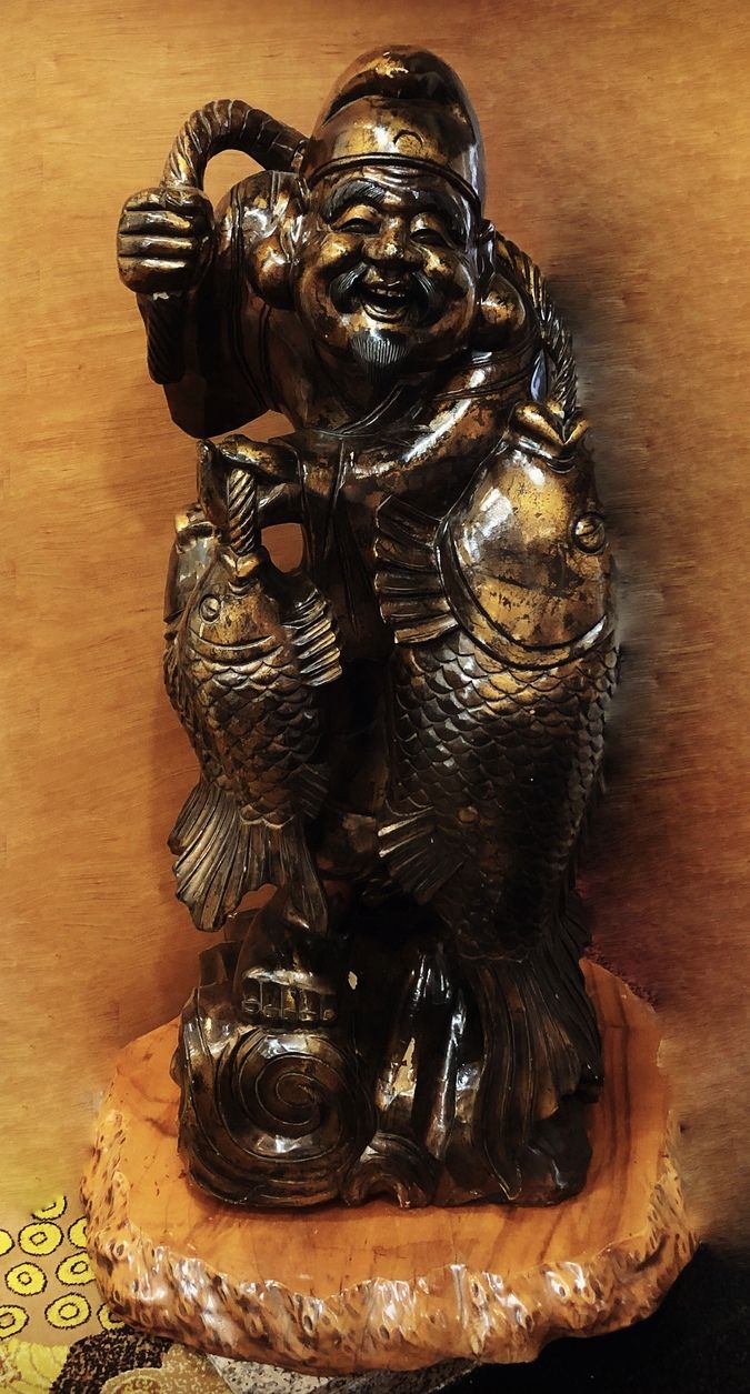 Escultura de madeira de um homem segurando um peixe.