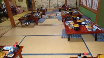 Um quarto japonês tradicional com tatames, mesinhas baixas e almofadas.