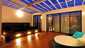 Interior moderno com deck de madeira, hidromassagem e sala envidraçada com vista.