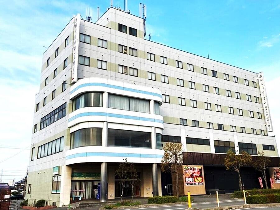 Um edifício de vários andares com entrada em esquina curva, grandes janelas e uma placa.