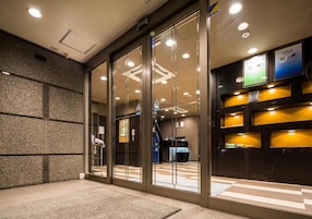 Uma área de recepção de hotel com portas de vidro, balcão de recepção e mesa de check-in.