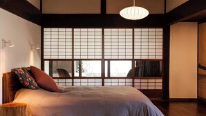 Quarto com cama grande, piso de madeira e parede com divisórias shoji.
