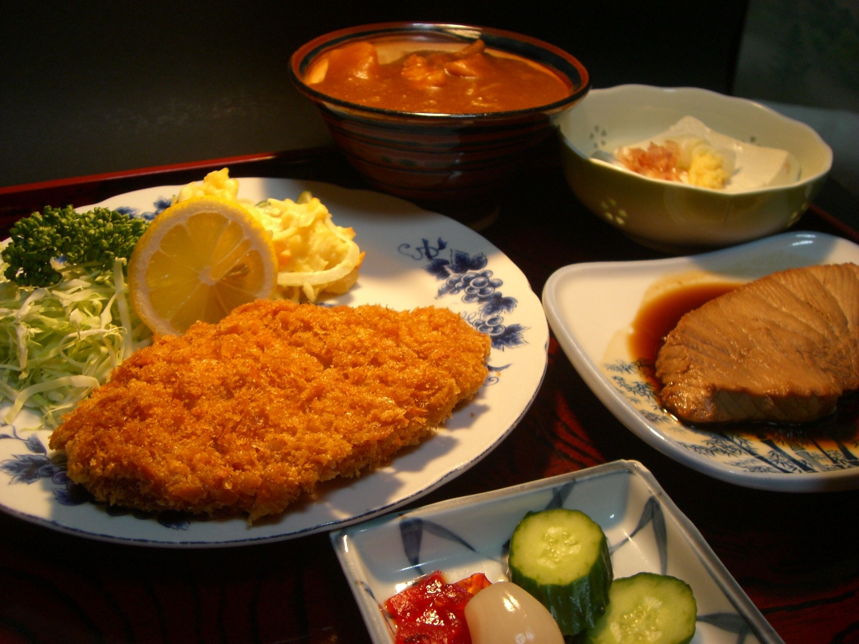 Refeição com escalope à milanesa, salada e sopa sobre uma mesa.