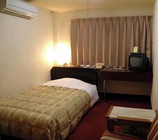 Quarto de hotel com cama, secretária e telefone, além de televisão.