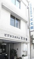 Um edifício com fachada em azulejos e uma placa que diz “ビジネスホテル天文館”, indicando que é um hotel de negócios com observatório.