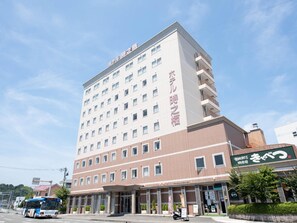 Um hotel de vários andares com fachada plana, muitas janelas e entrada no nível da rua.