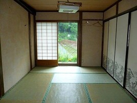 Um quarto japonês tradicional com tatames, portas deslizantes e vista para um jardim.
