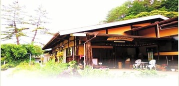 Um edifício tradicional japonês com varanda coberta, vigas de madeira e uma placa.