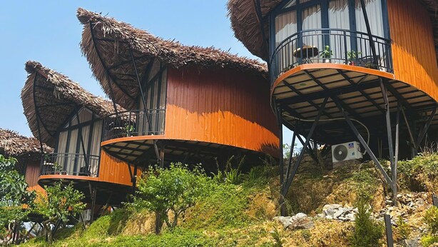 Conjunto de construções com telhados de palha e varandas, localizado numa encosta.