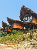 Conjunto de construções com telhados de palha e varandas, localizado numa encosta.