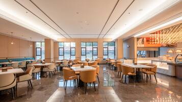 Um restaurante espaçoso com várias mesas e cadeiras, grandes janelas e design de interiores moderno.