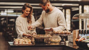 Disposição de buffet com diversos alimentos e uma vitrine de vidro.