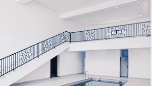 Piscina interior moderna com guarda-corpo geométrico e vista clara do revestimento em azulejo do fundo.
