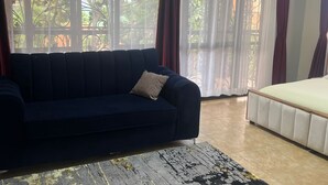 Um quarto com um sofá azul escuro, uma cama branca e um tapete estampado.