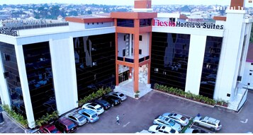 Um hotel com design moderno, apresentando uma entrada imponente e estacionamento com vários carros.