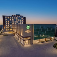 Um edifício moderno de hotel com uma placa destacada para 'HOTEL GRAND MAYA by artotel'.