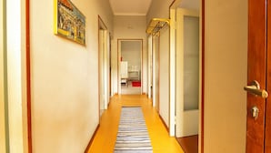Um corredor estreito com um tapete estampado, portas de madeira e um quadro na parede.