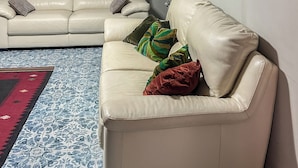Uma sala de estar com um sofá bege, um tapete estampado e três quadros na parede.
