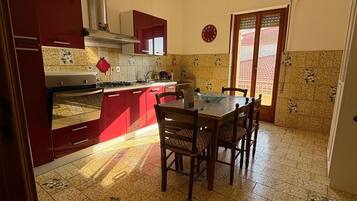 Um frigorífico, um forno, uma placa de cozinha, utensílios de cozinha