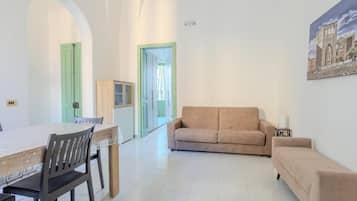 Uma sala de estar ampla, com uma mesa de jantar, dois sofás e um quadro na parede.