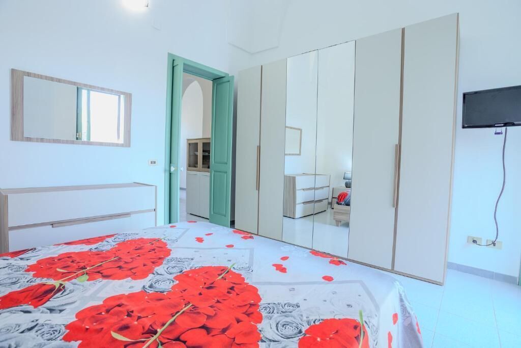 Um quarto com cama, guarda-roupa, espelho e televisão.