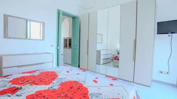 Um quarto com cama, guarda-roupa, espelho e televisão.