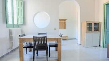 Uma sala de jantar com uma mesa redonda, cadeiras, um radiador e um armário.