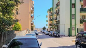 Uma rua flanqueada por edifícios residenciais de vários andares, cada um com varandas e um estilo arquitetônico uniforme.